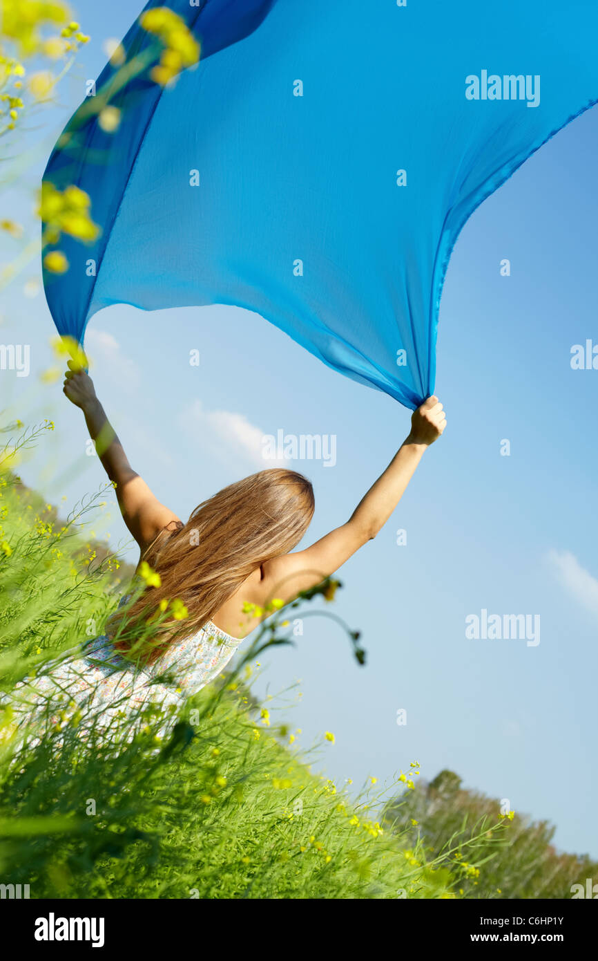 Portrait of charming young girl raising her hands with blue chiffon in ...