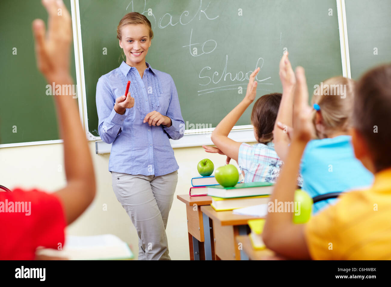 Portrait of smart teacher by blackboard looking at schoolkids in ...