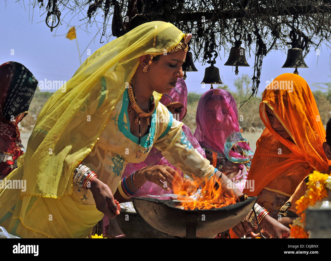 Tribal woman making offering at alter Aravalli Hills Rajasthan India ...