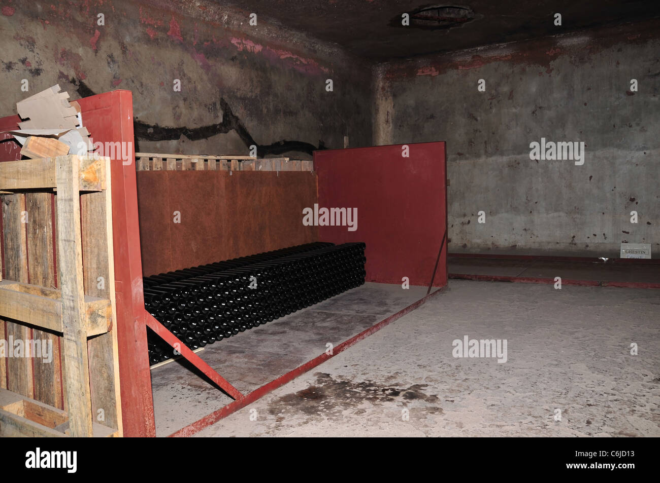 Black wine bottles stacked in an open front wooden crate, wine cellar ...