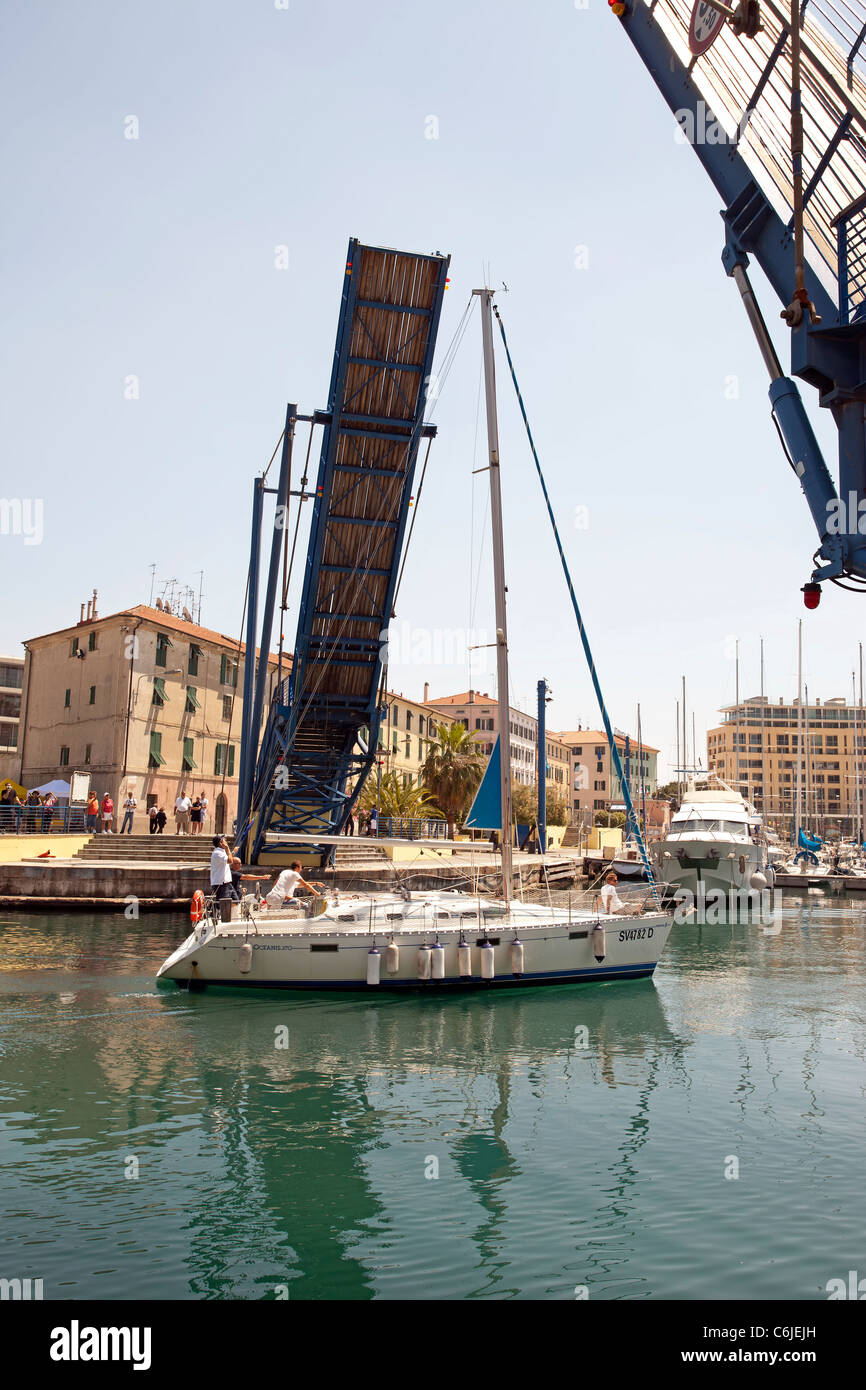 Sailboat in Savona, Italy marina harbor sails under a draw bridge ...