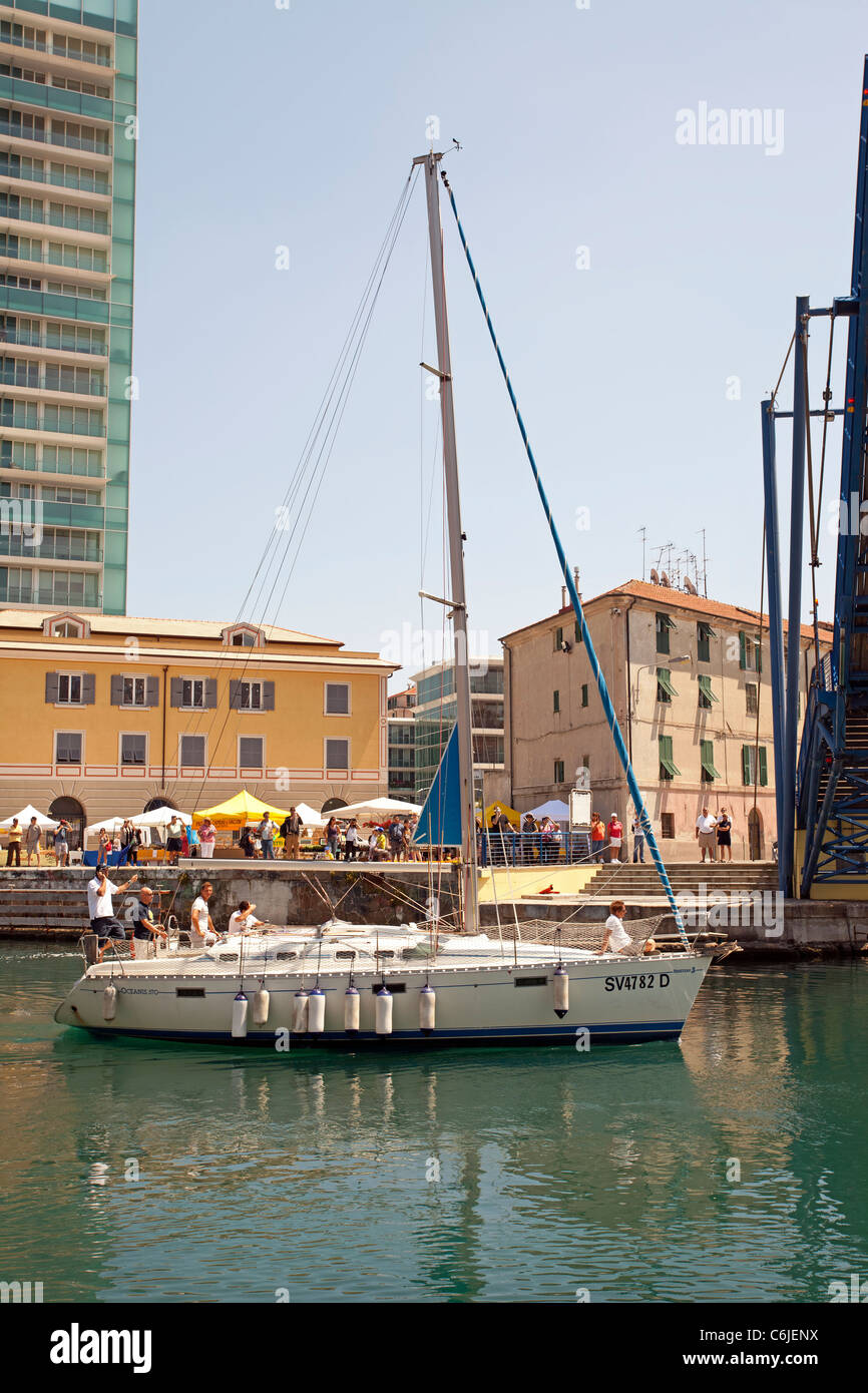 Sailboat in marina harbor sails under a draw bridge. Vertical view ...