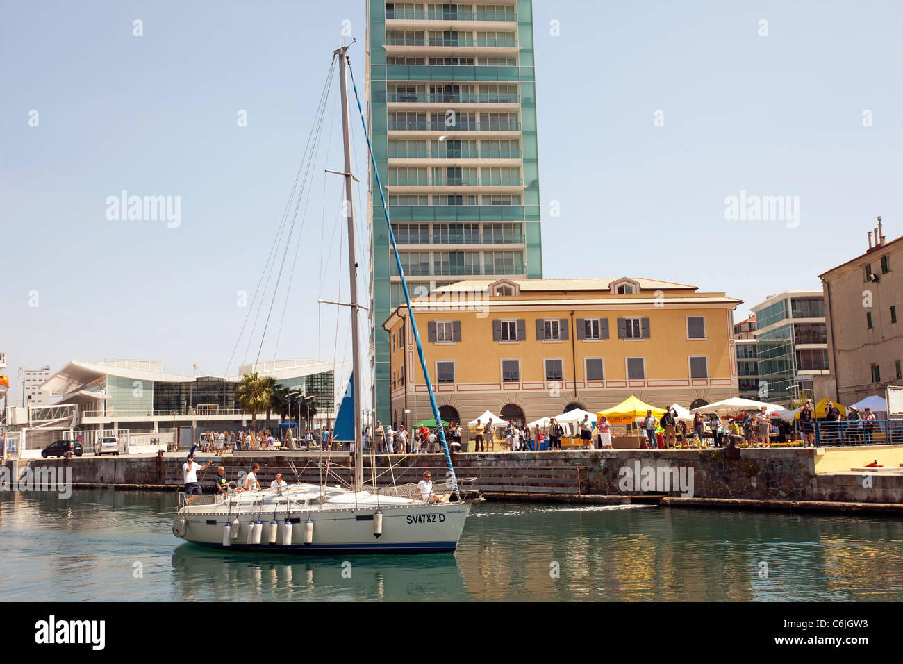 Sailboat in marina harbor sails under a draw bridge. Wide angle view ...