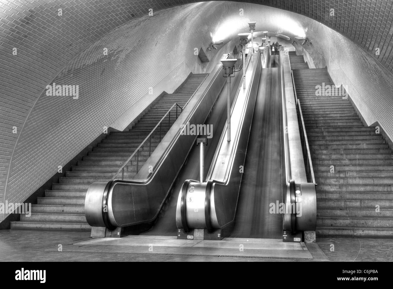 Tunnel with a long row moving stairways leading deep down to the ...