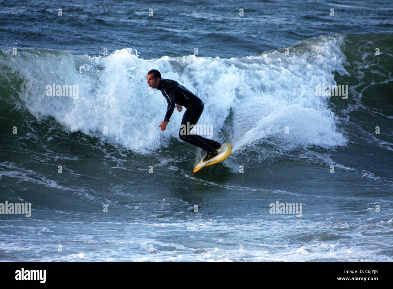 Surfer riding the waves off Peel, IOM UK Stock Photo - Alamy