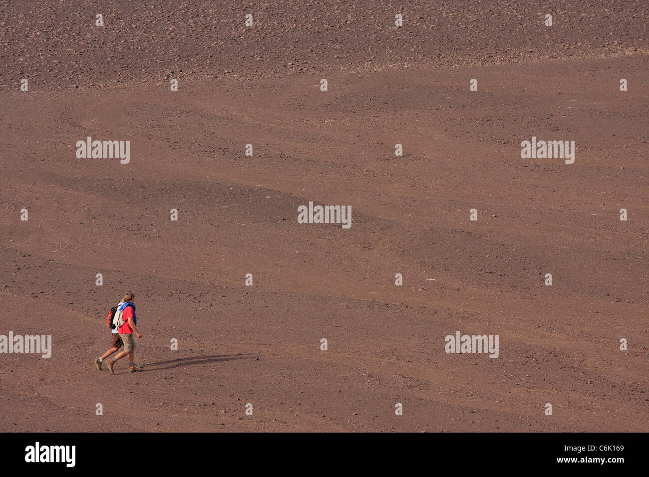 Two hikers walking in step across an arid and barren plain Stock Photo ...