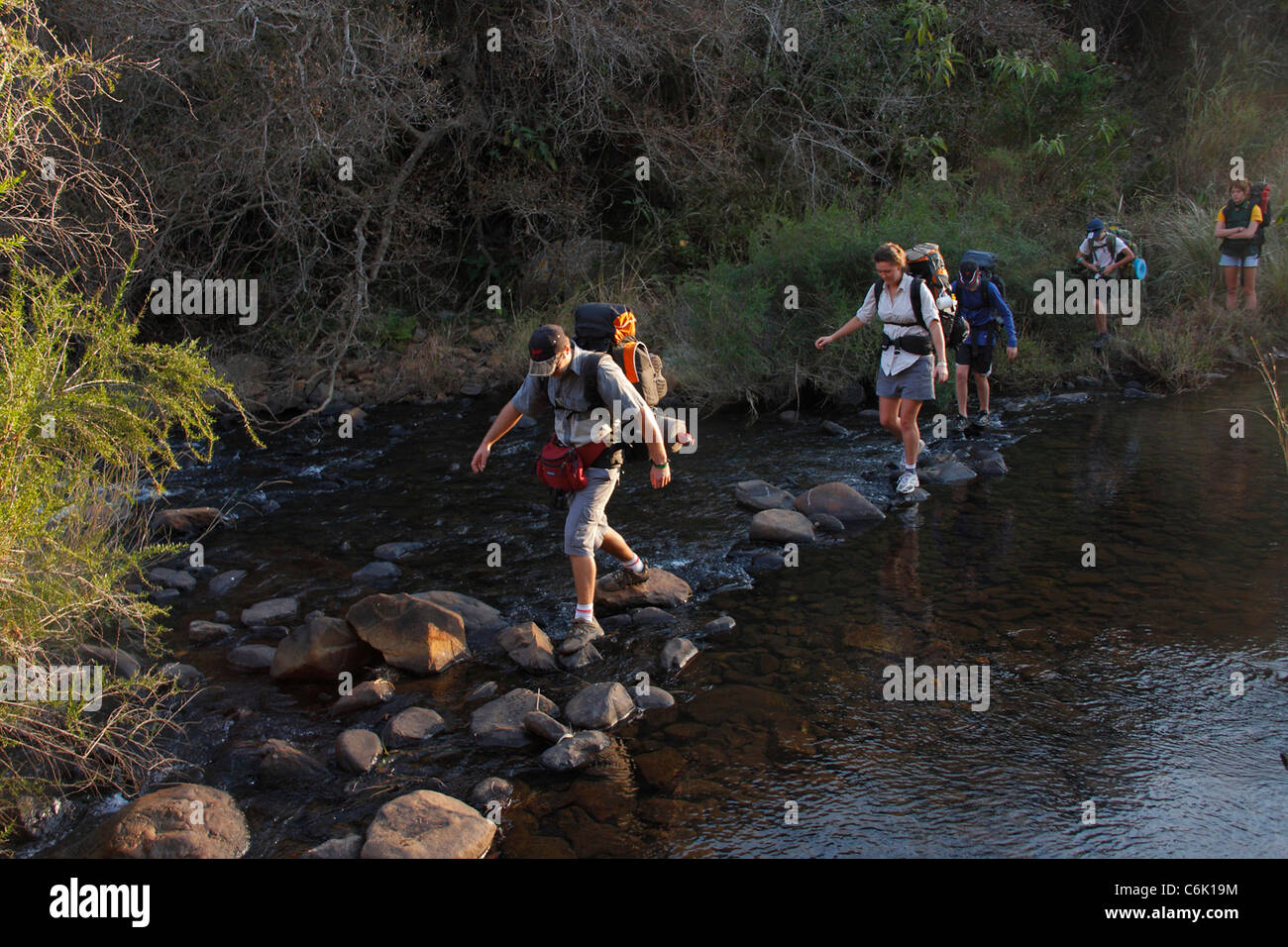 Hikers crossing mountain stream Stock Photo - Alamy