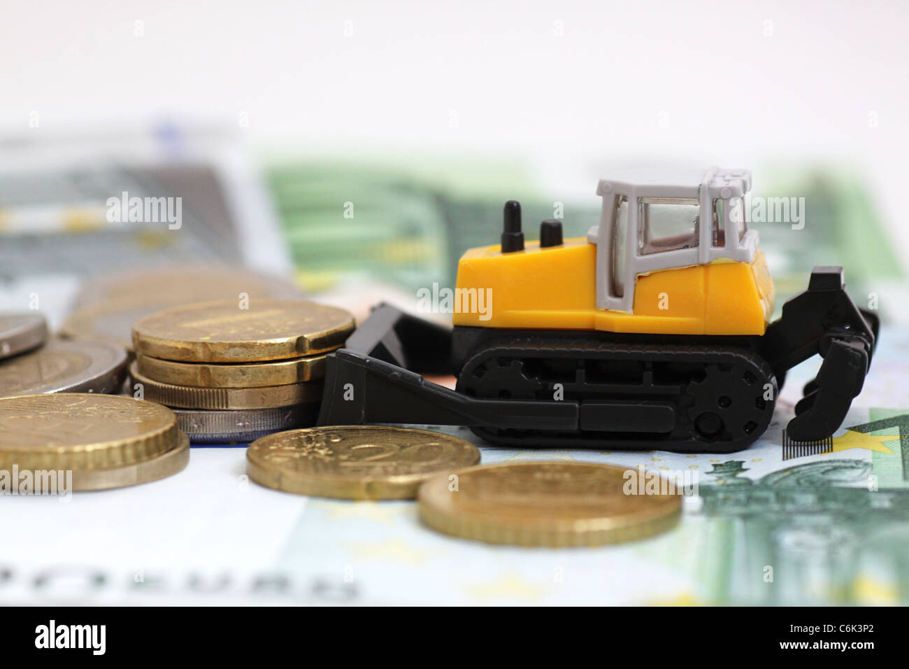 rake in heaps of money: tractor pushing heap of coins Stock Photo - Alamy