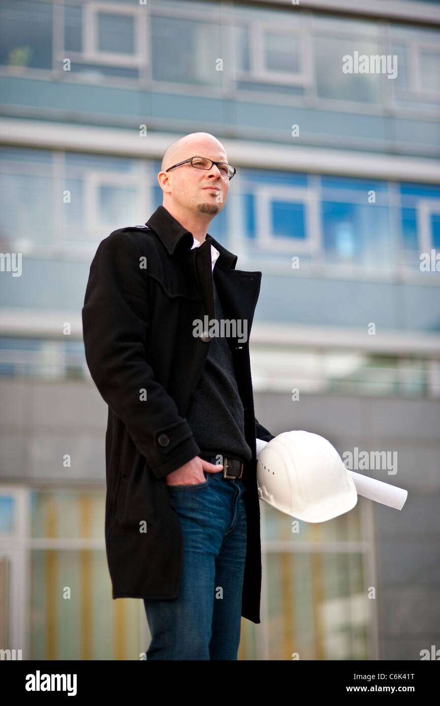 Architect with helmet and plan in front of a modern facade Stock Photo ...