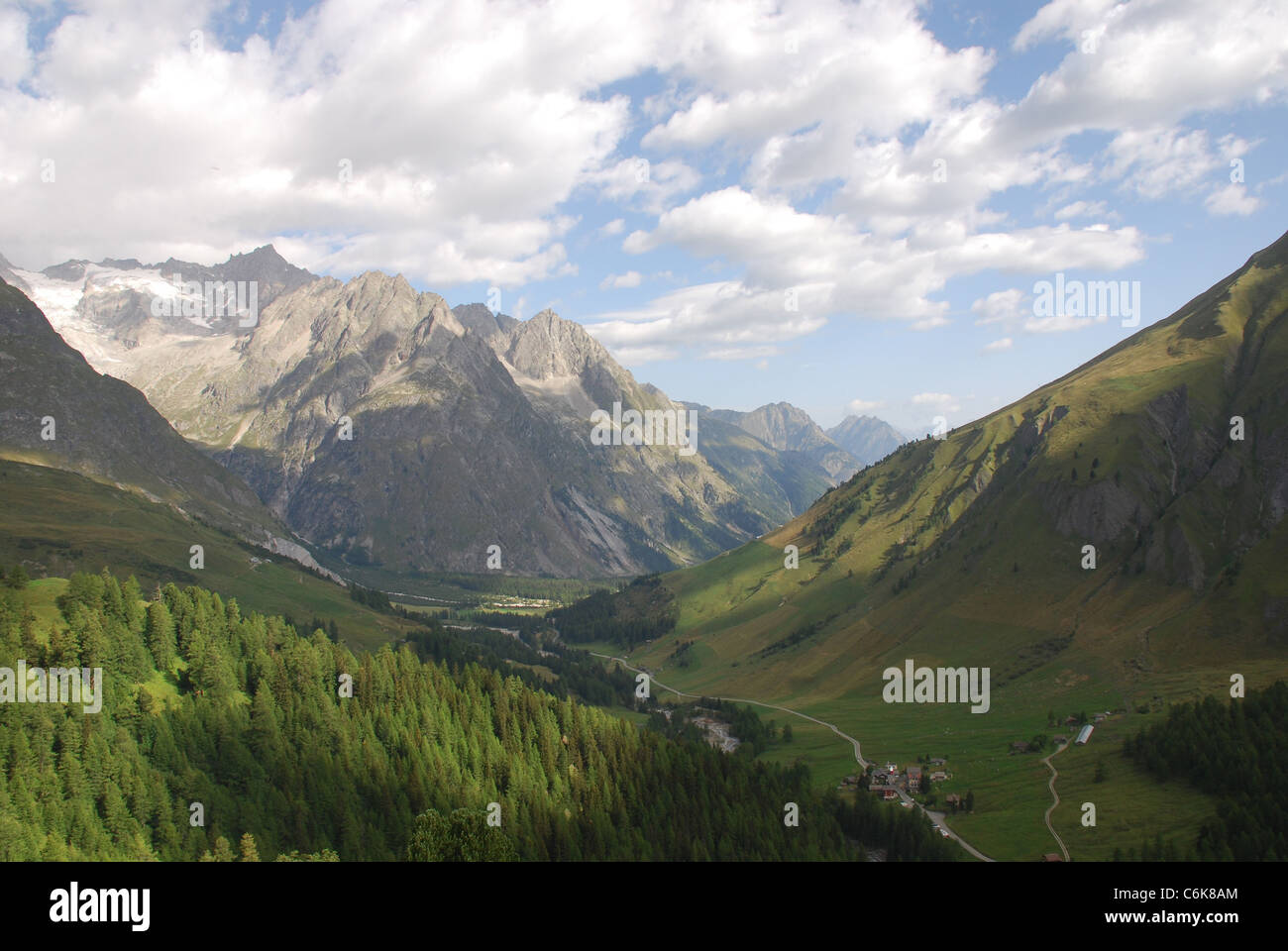a valley in the alps with forest clouds and high mountains in the ...