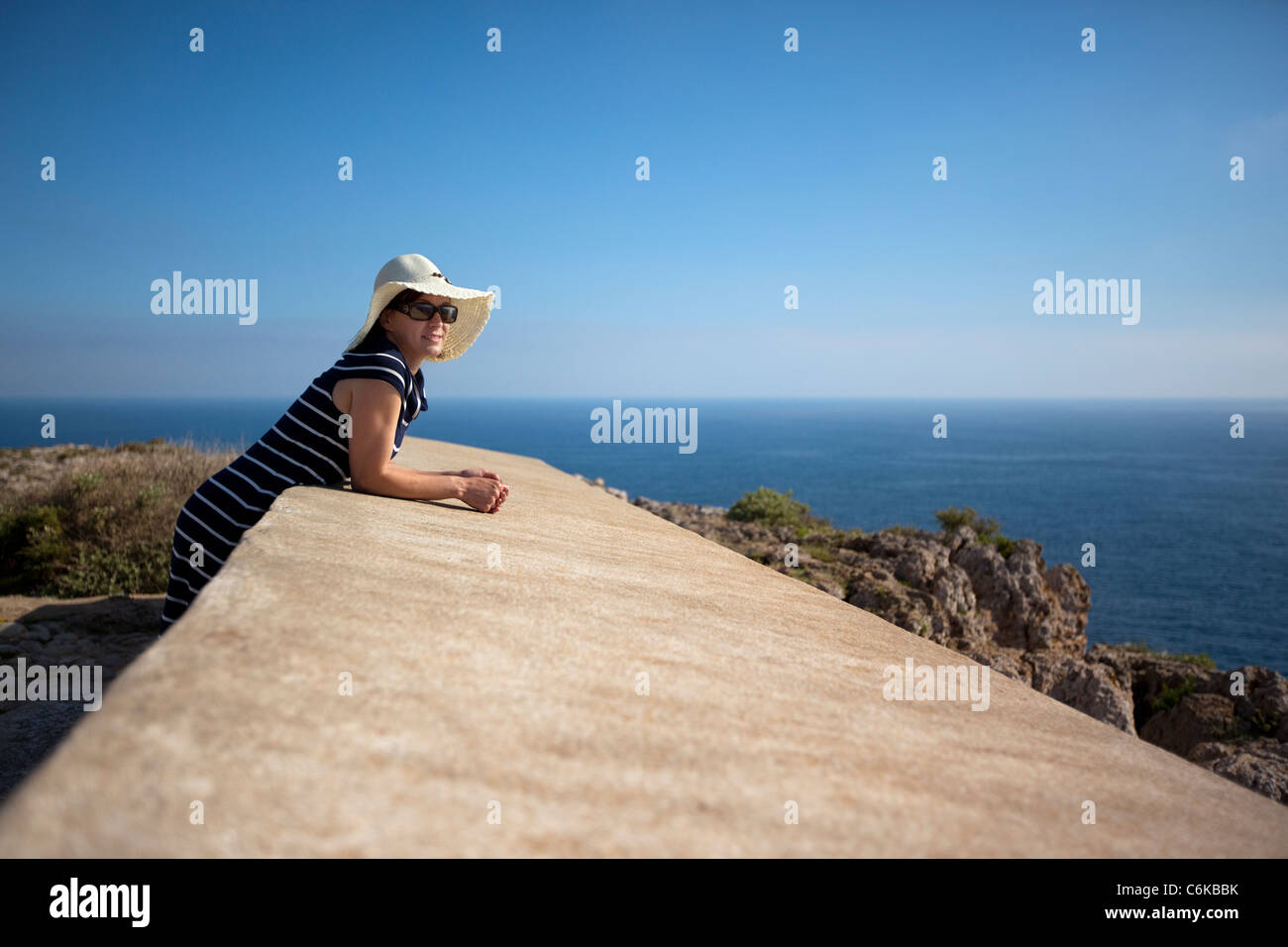 Attractive woman in hat looking out over ocean from atop cliff Stock ...