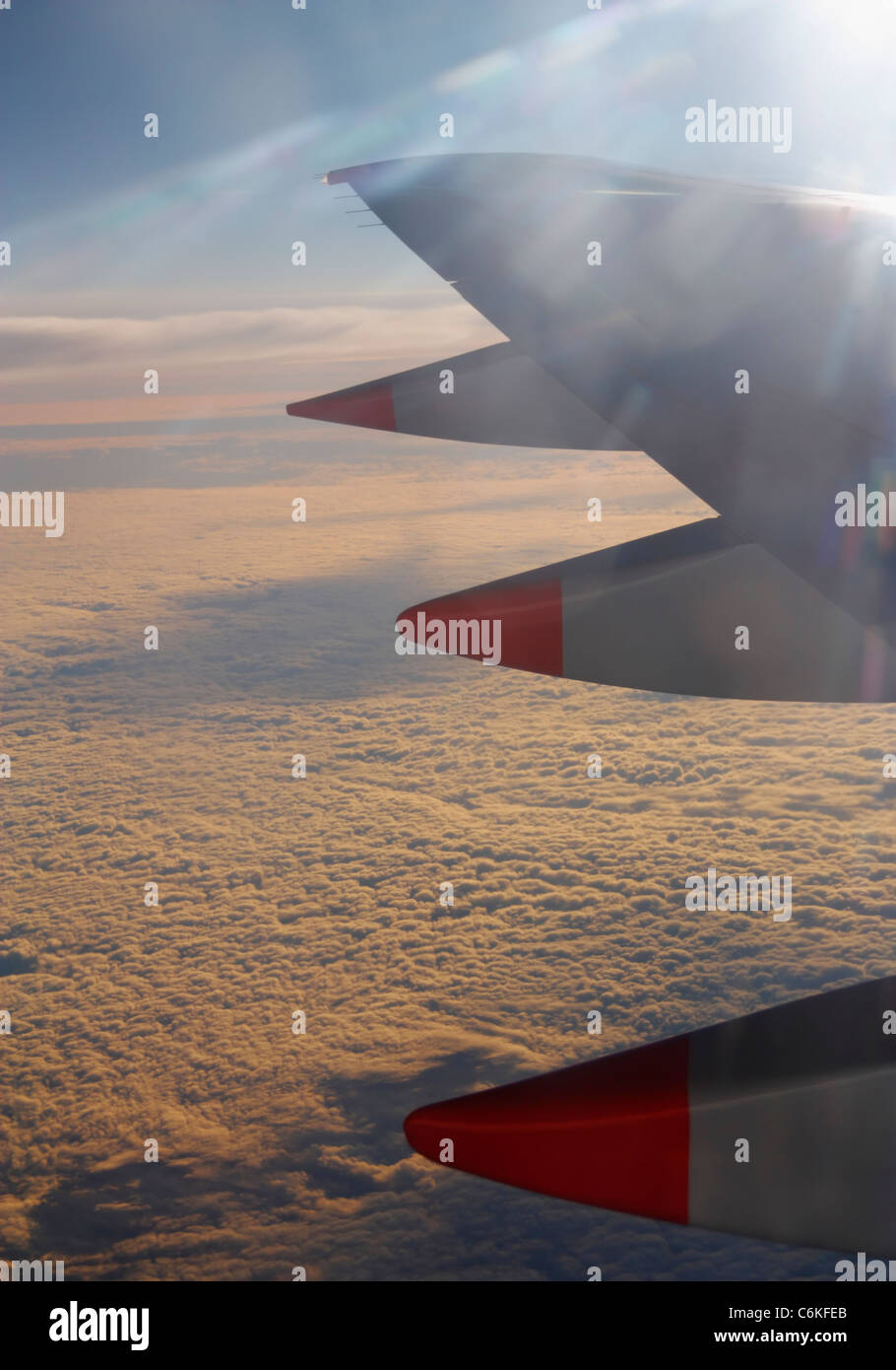 View from window seat of airplane wing over layer of cloud at sunset ...