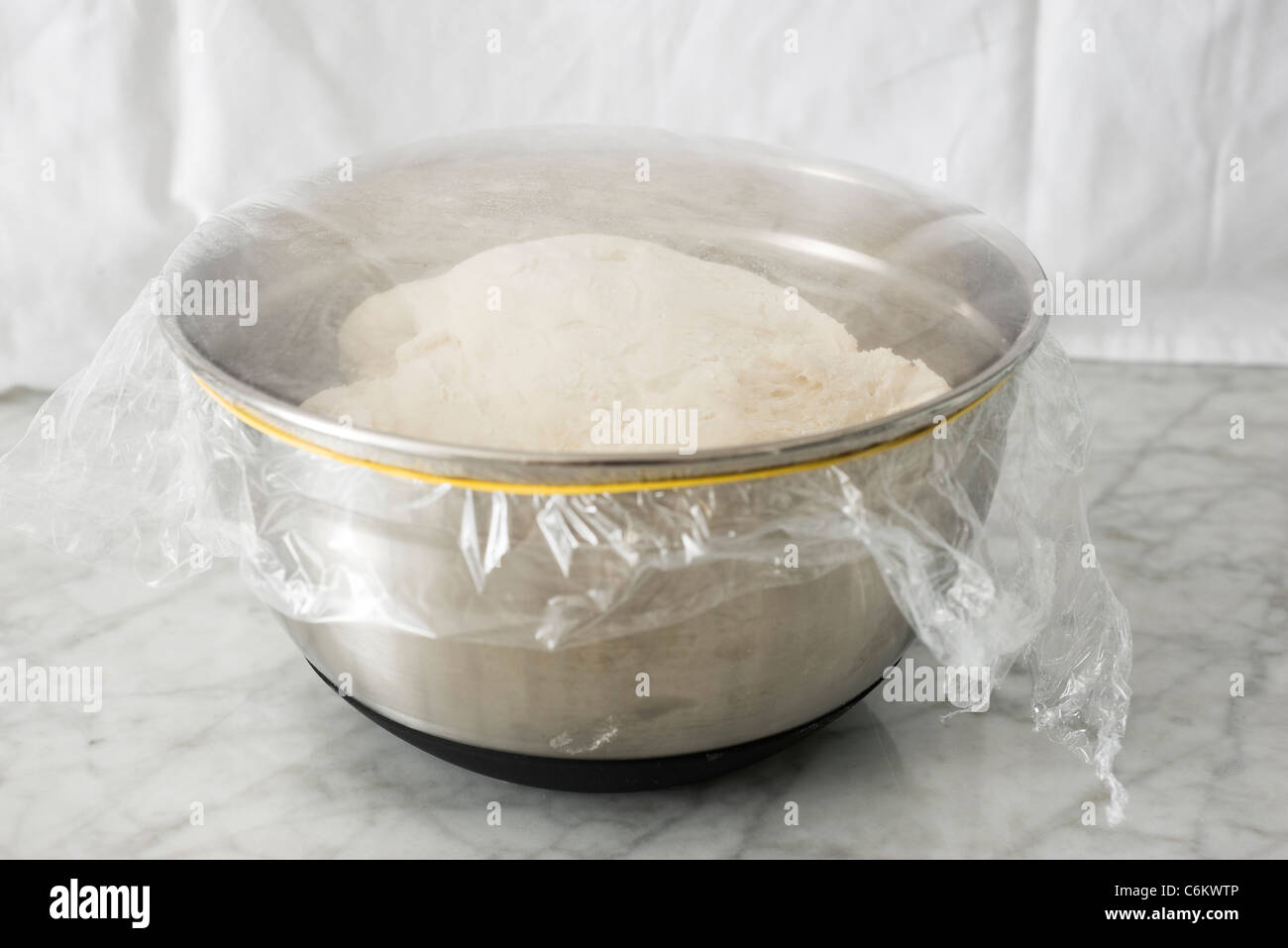 Basic bread dough rising in covered bowl Stock Photo - Alamy