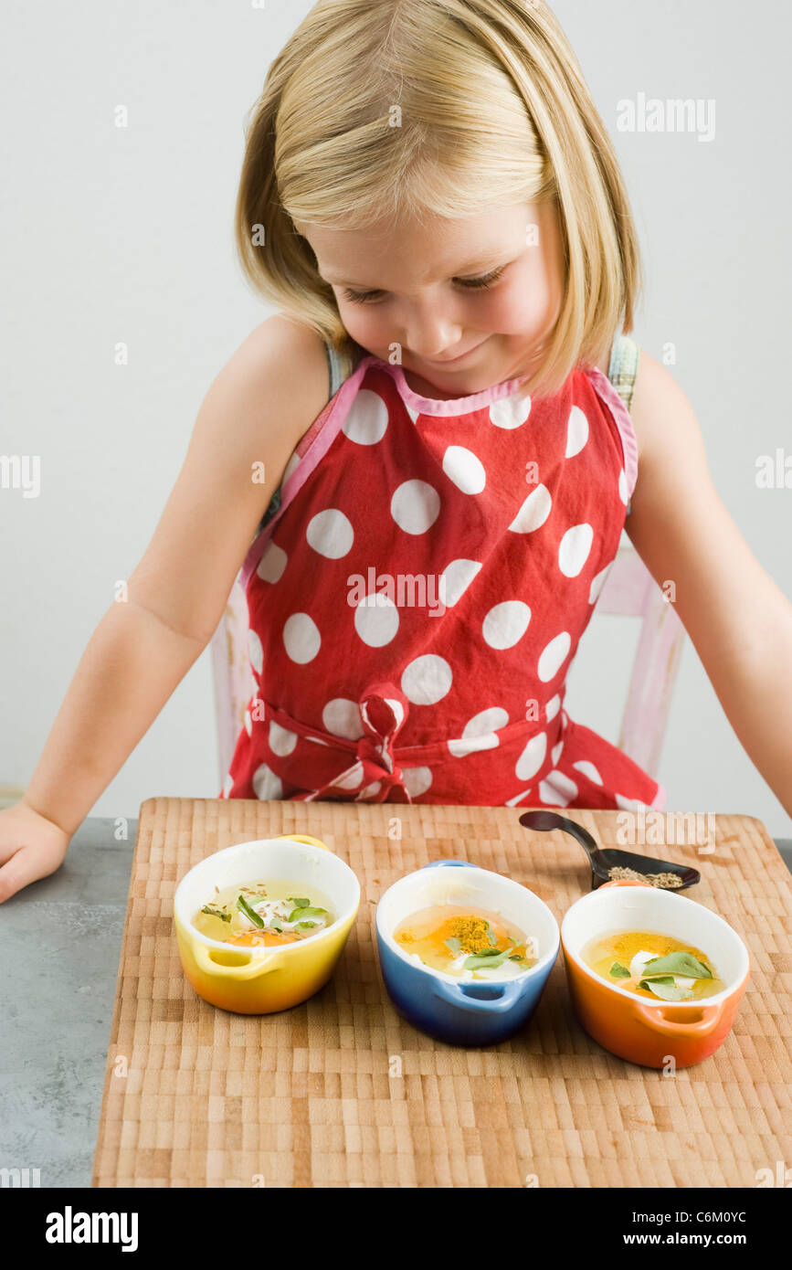 little-girl-preparing-baked-eggs-in-small-casserole-dishes-stock-photo