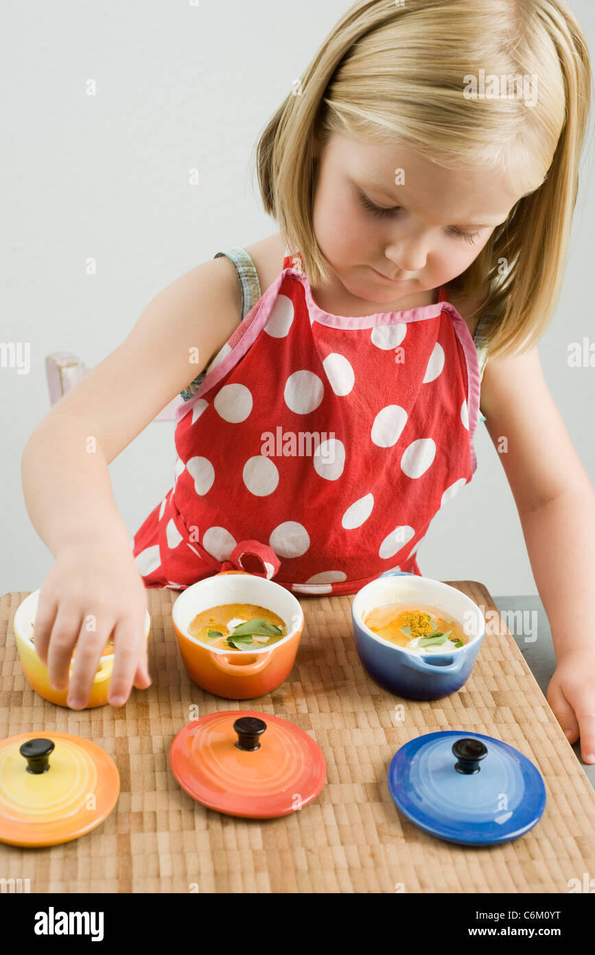 Little Girl Preparing Baked Eggs In Small Casserole Dishes Stock Photo
