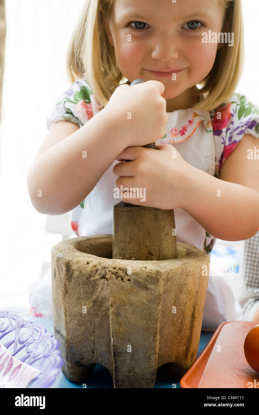 Little girl grinding ingredients with mortar and pestle Stock Photo - Alamy