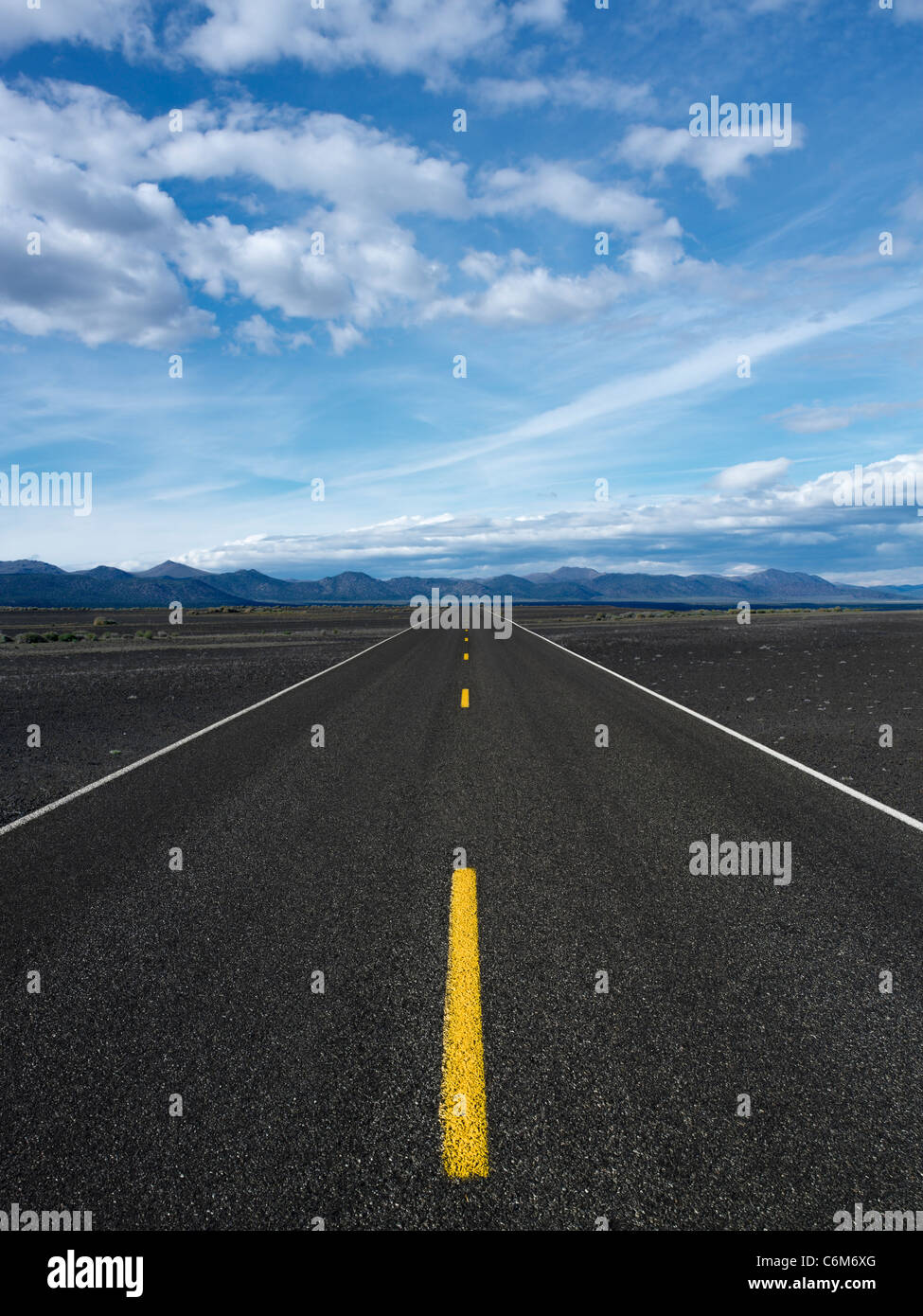 blacktop highway running through landscape of black sand Stock Photo ...