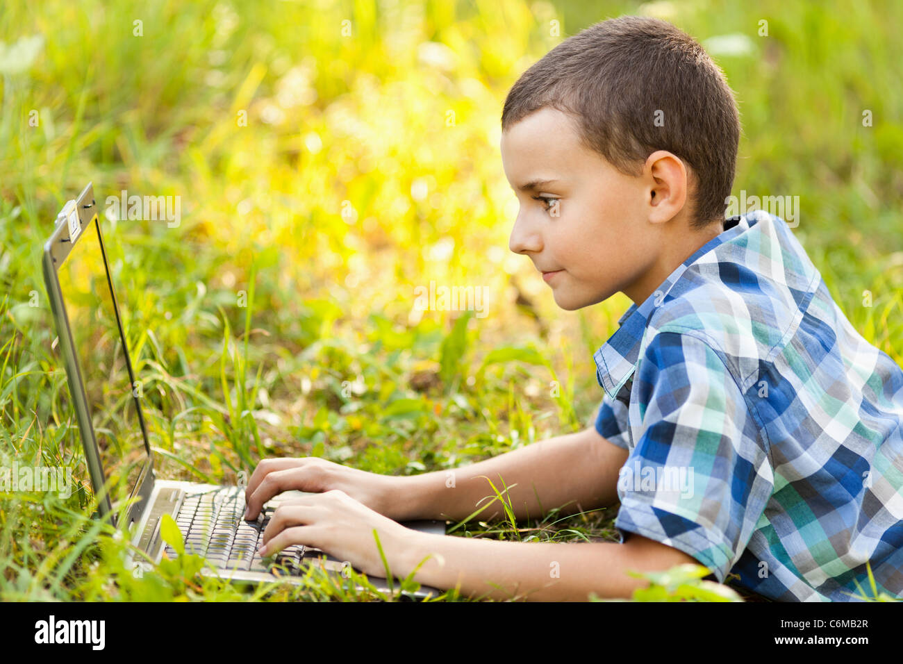 School boy using his laptop outdoor on a meadow Stock Photo - Alamy