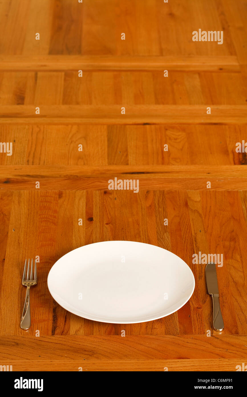 Wooden table with a single plate and cutlery. Lots of space for copy ...