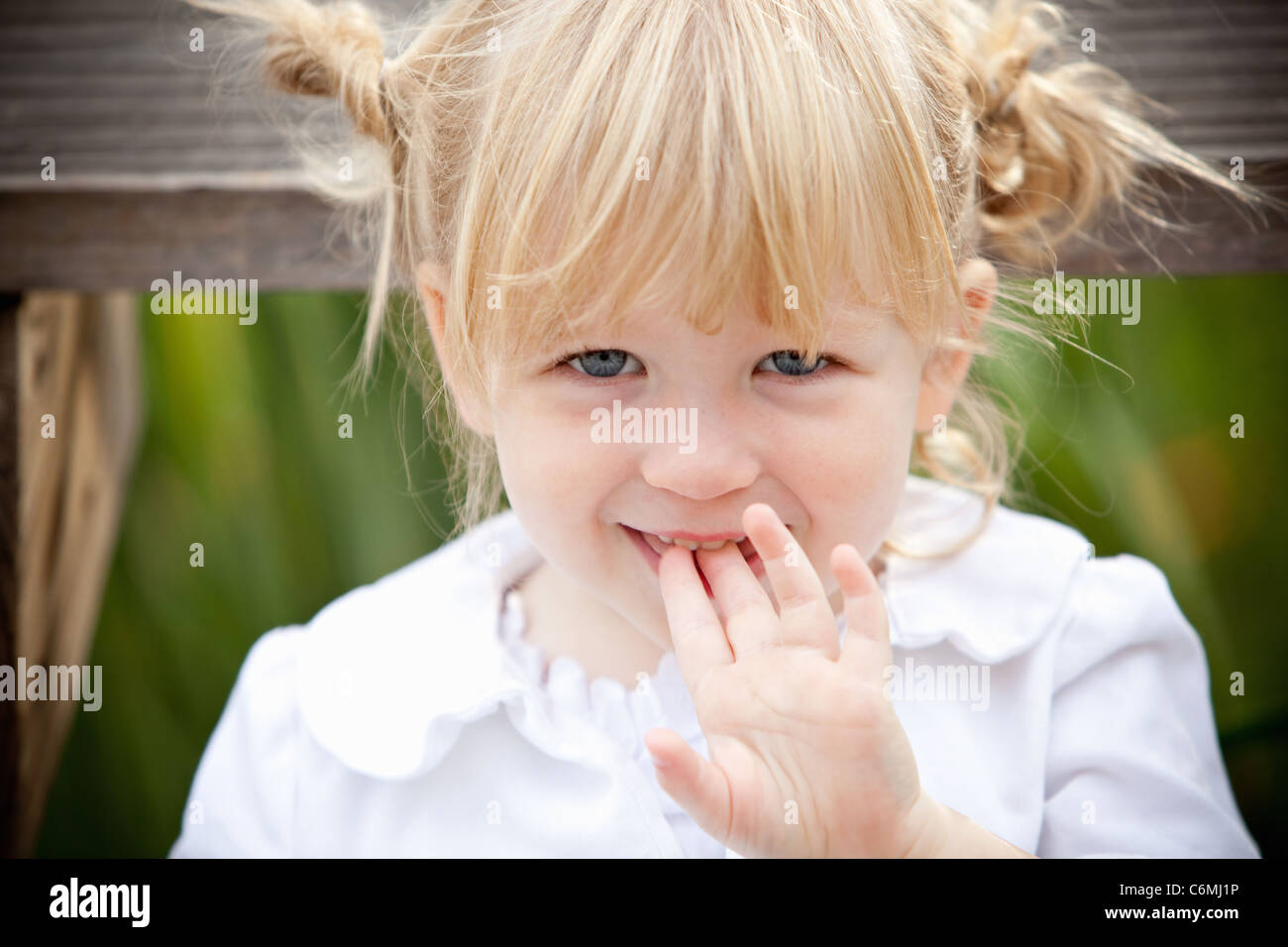 Blonde girl biting her fingers and smiling Stock Photo - Alamy