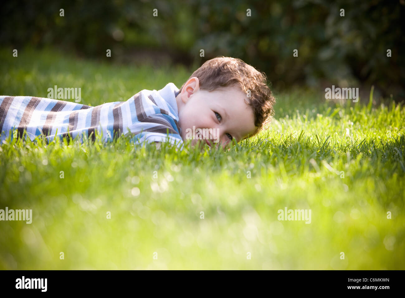 Young boy lying in the grass Stock Photo - Alamy