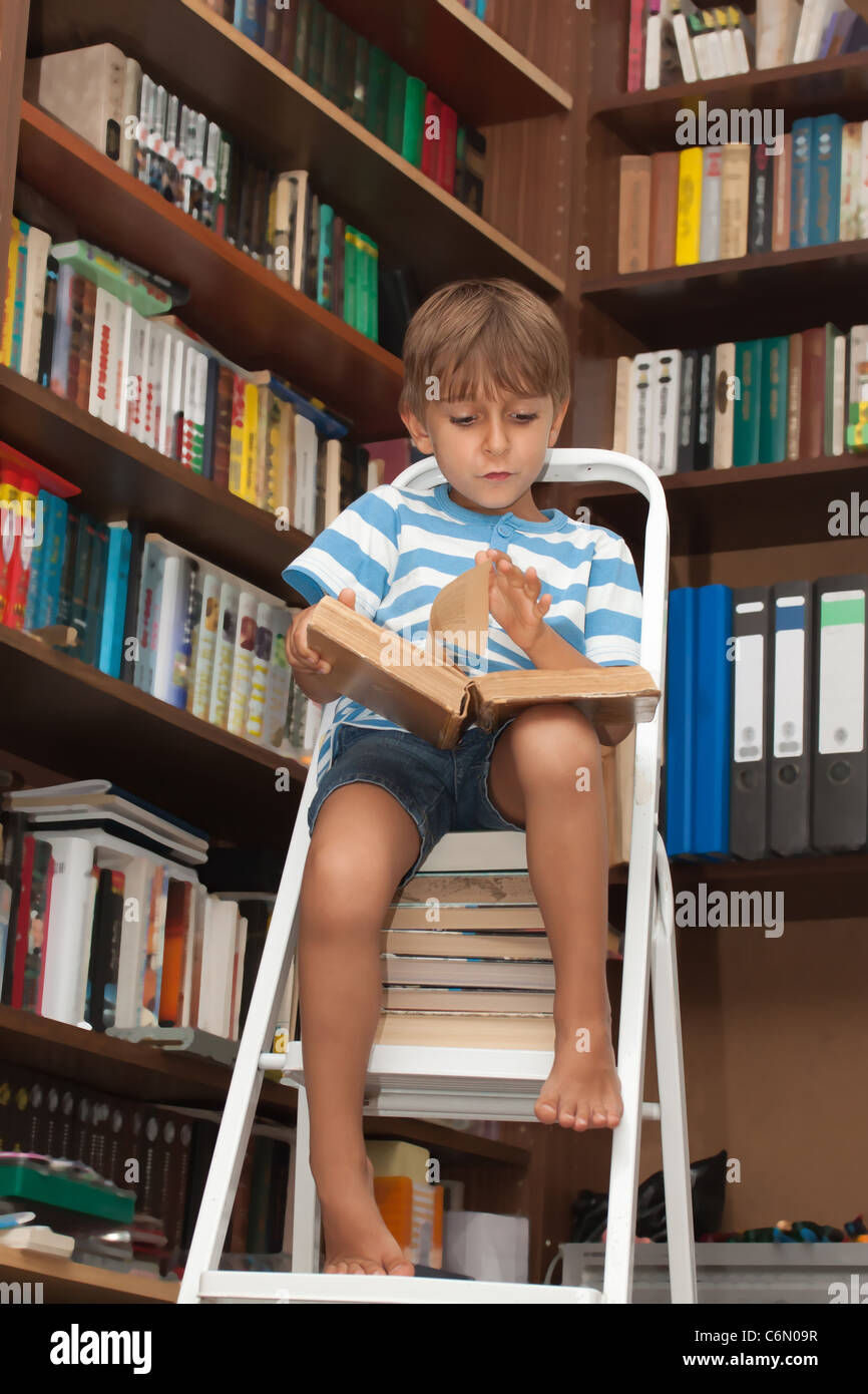 Boy in library reading book Stock Photo - Alamy