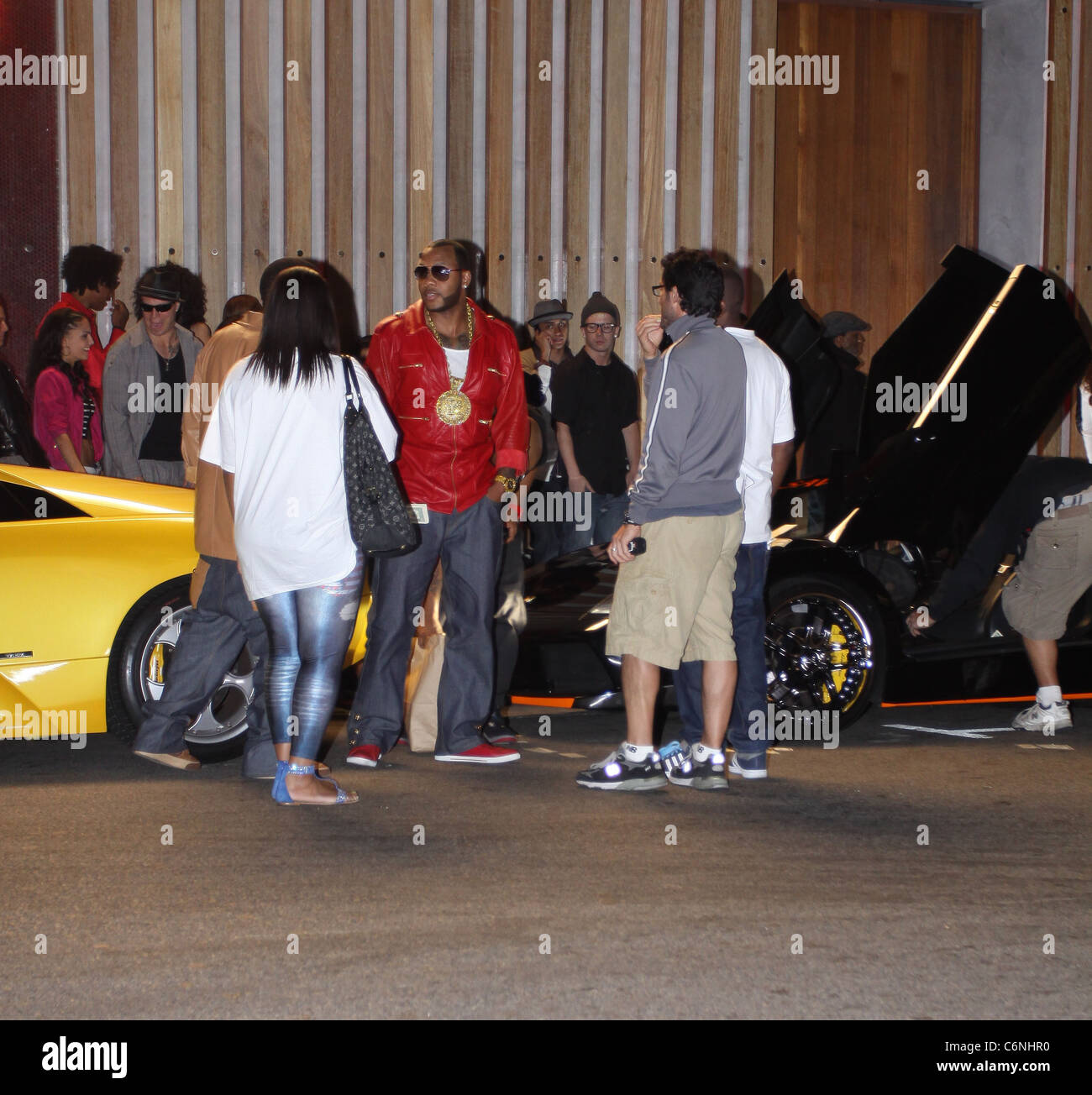 Flo Rida (C) stands next to some luxurious cars on the set of his new ...