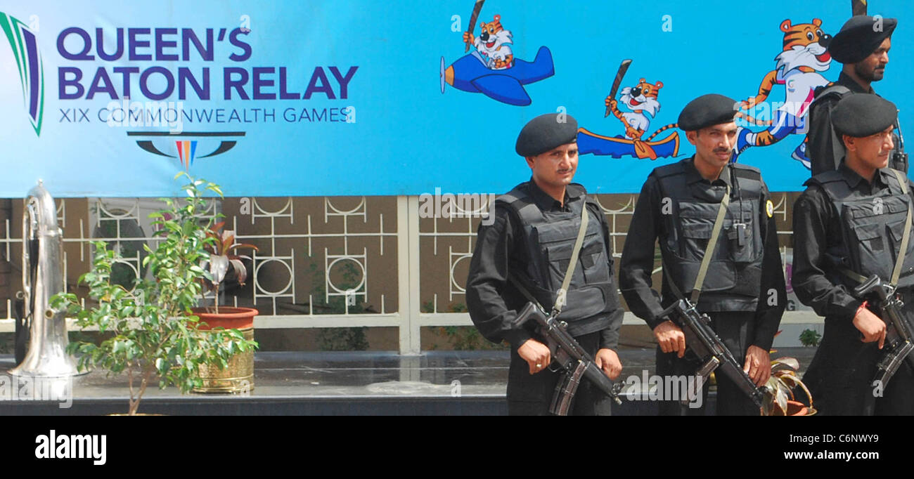 Indian security personnel stand in front of a sign showing The Queen's ...