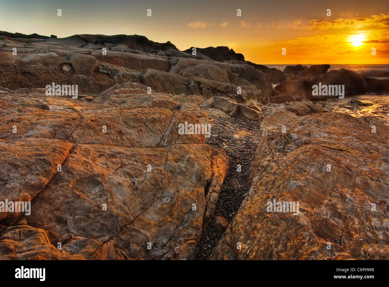 Golden sunset along a rocky coast showing the details using HDR Stock ...