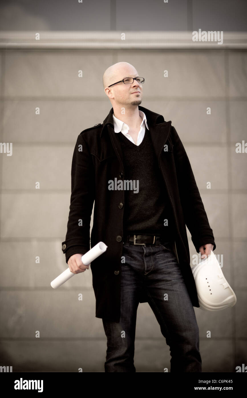 Architect with helmet in his left and construction plan in his right ...