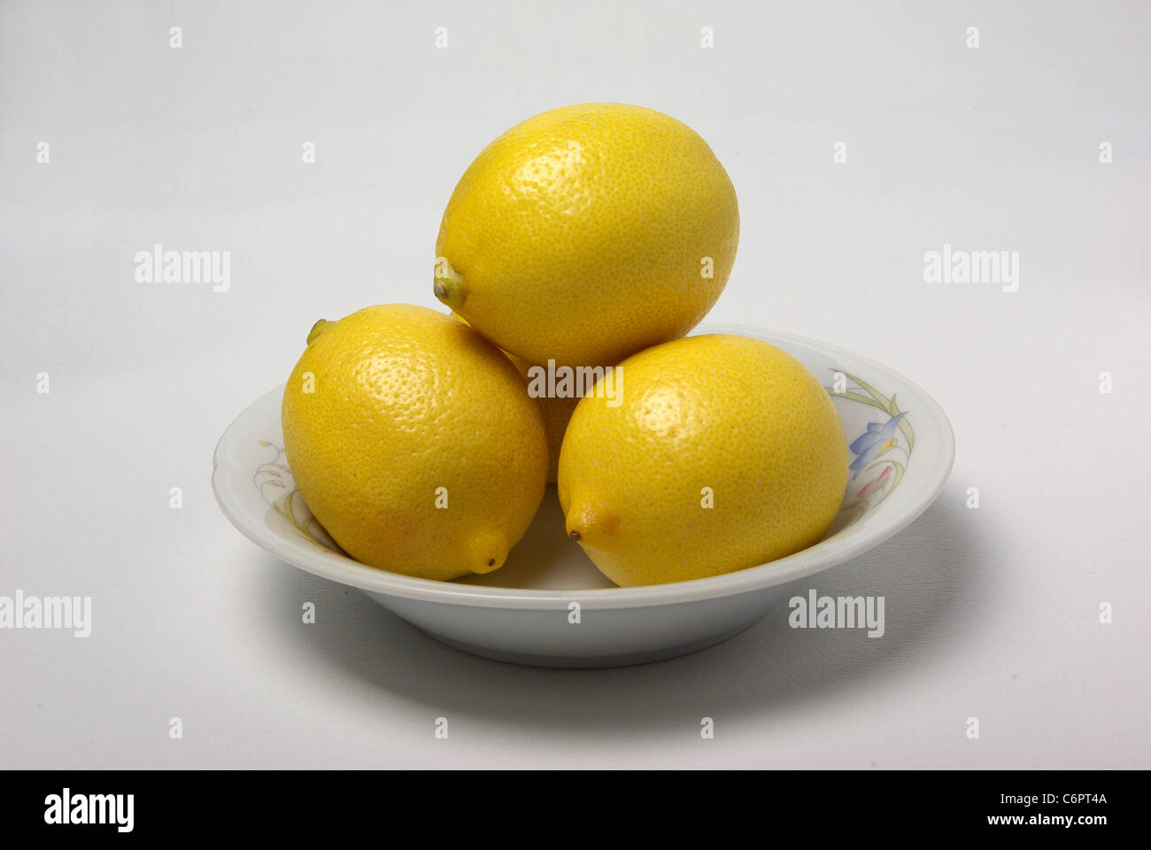 Four lemons sit in a small bowel on a plain white background Stock ...