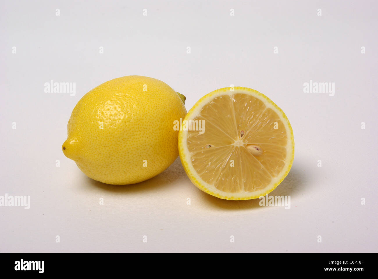 A whole and a half of a lemon sit on a white background Stock Photo - Alamy
