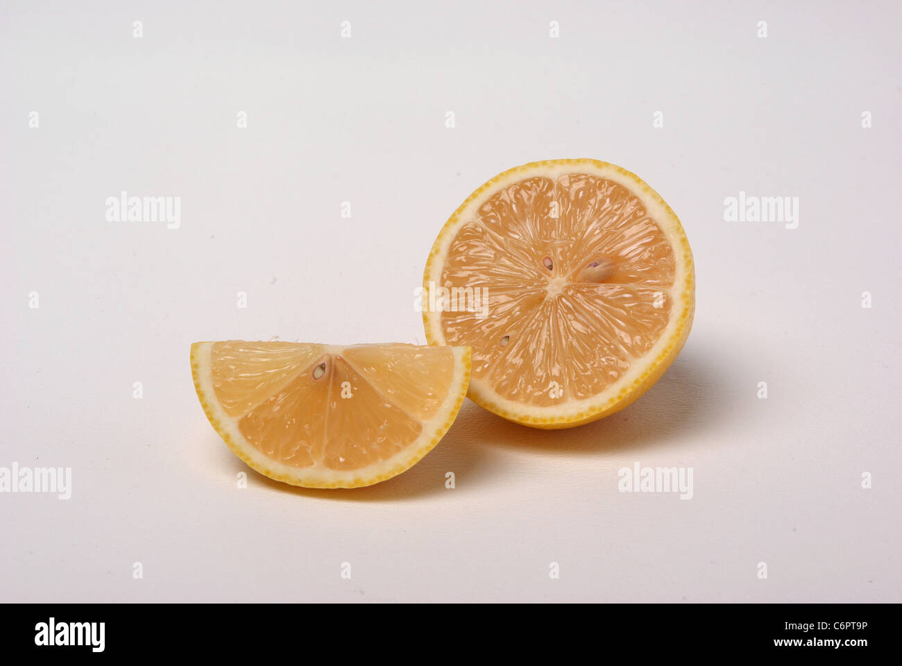 A whole lemon and a quarter of a lemon sit on a white background Stock ...