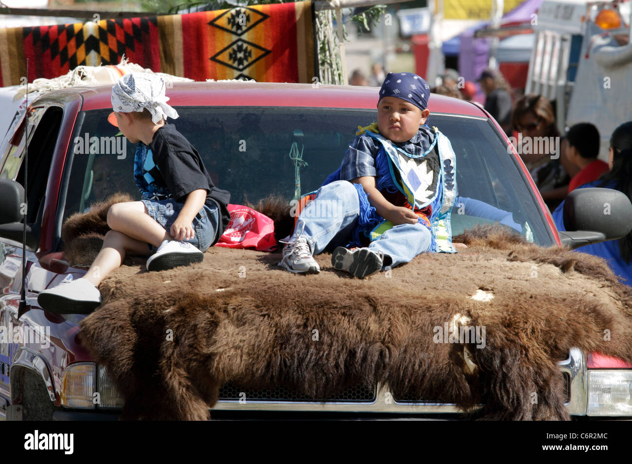 Young Native American boys riding on a car fitted with a bison hide ...
