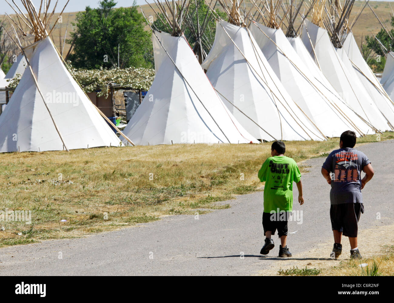 Two young Native Americans walking along a row of teepees on the Crow ...