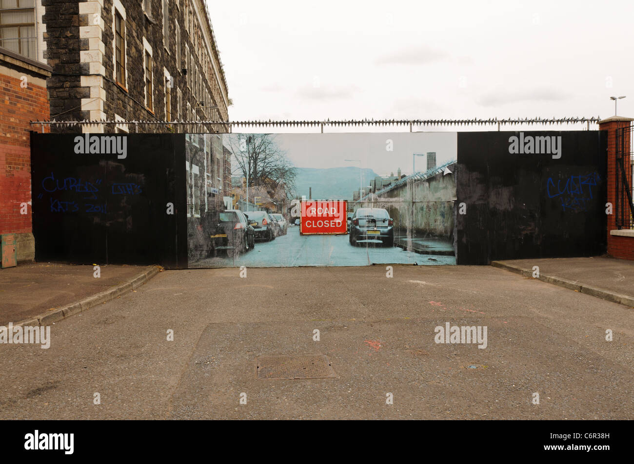 Closed gate across a road at one of the Belfast "Peace Walls", covered ...