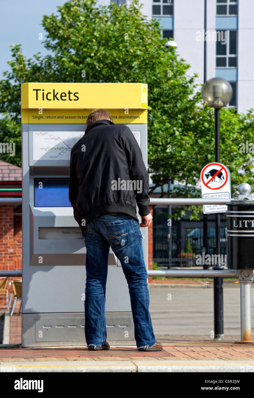 Man buying a ticket for Metrolink tram at a machine on a tram station ...