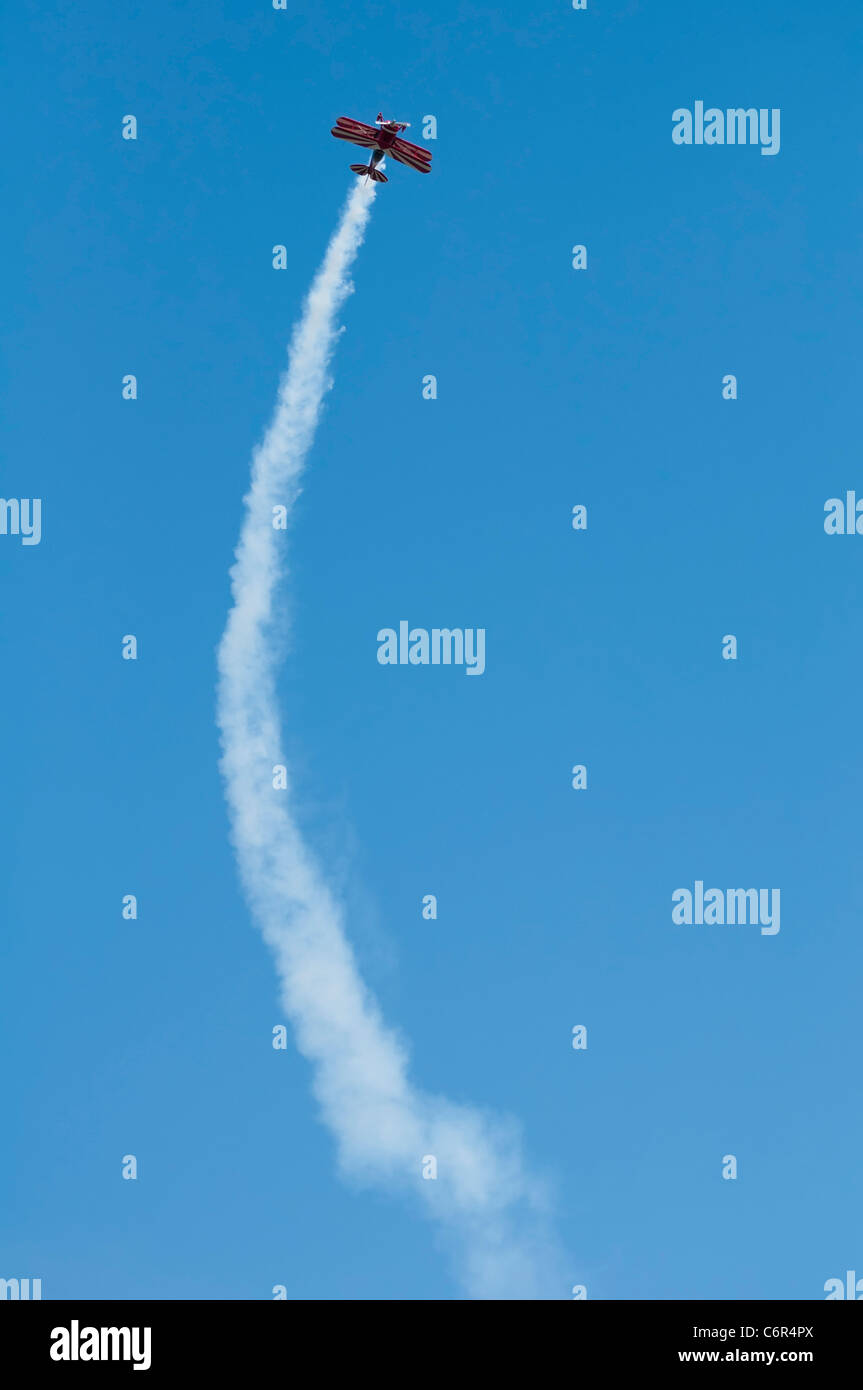 Red plane looping in a blue sky. Vertical image Stock Photo - Alamy