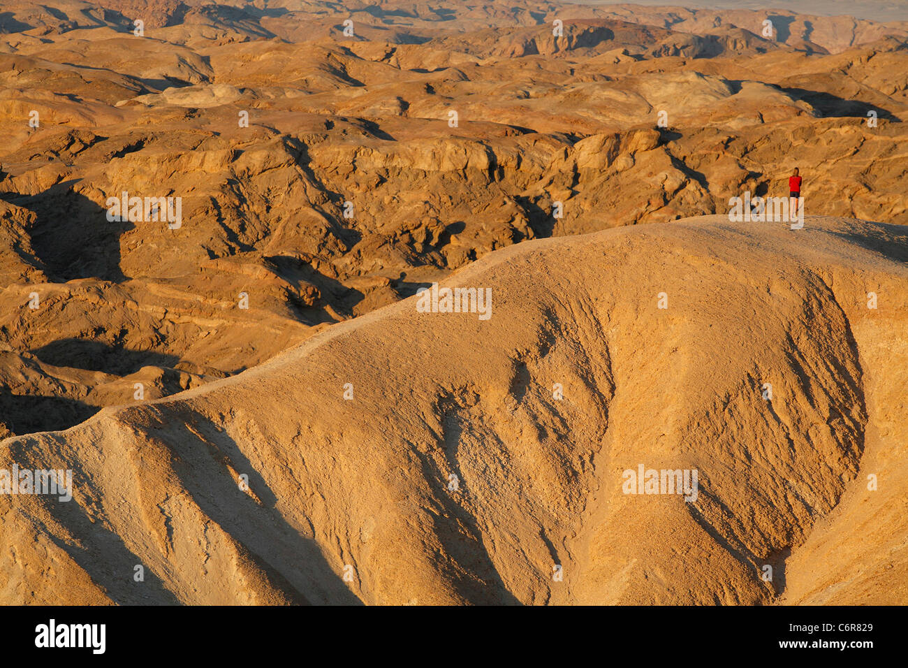 Desert landscape with girl looking over valley below from a high ridge ...
