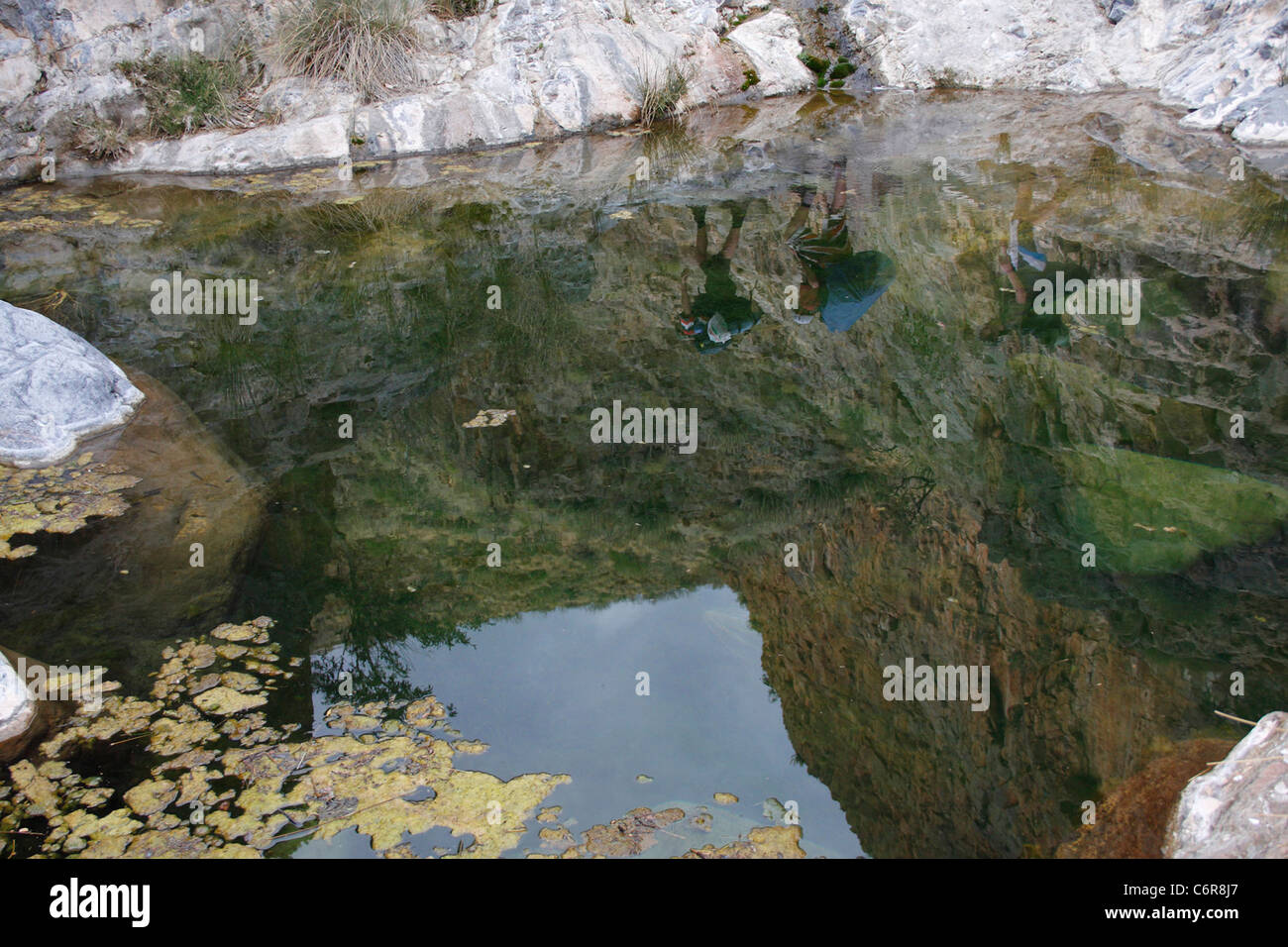 Hikers reflected in mountain pool Stock Photo - Alamy