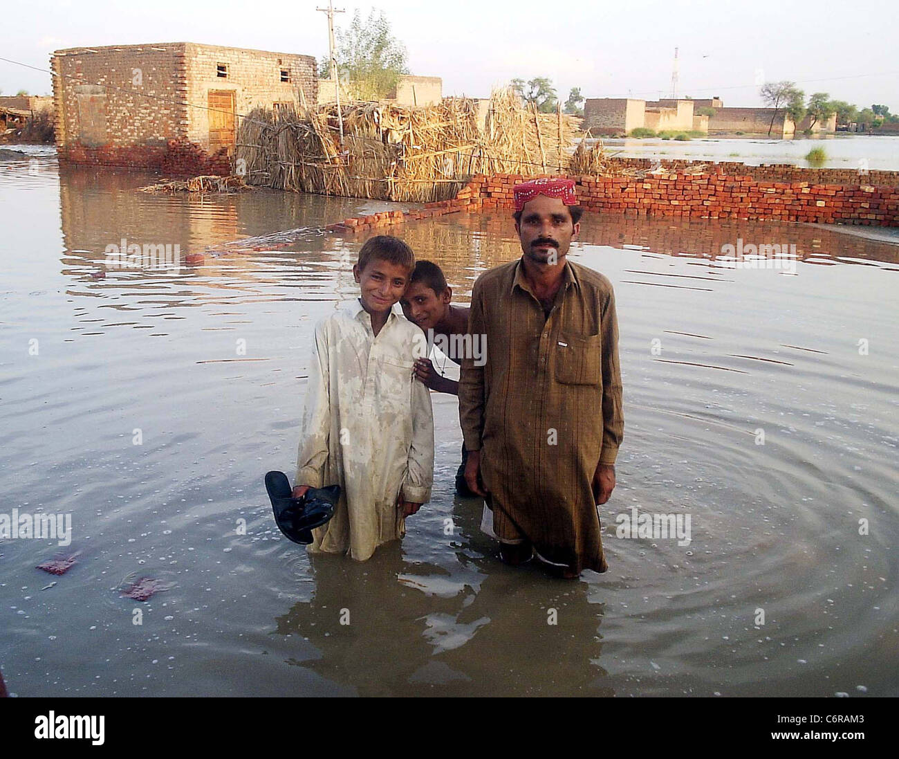 Rain-affected man and children pass through a flooded area Stock Photo ...