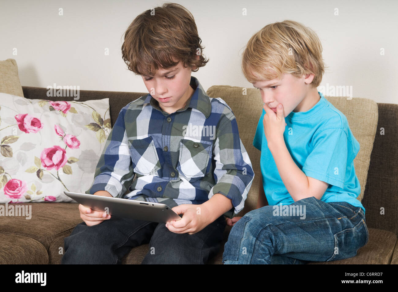 Kid is working on a tablet computer while his brother is watching Stock ...