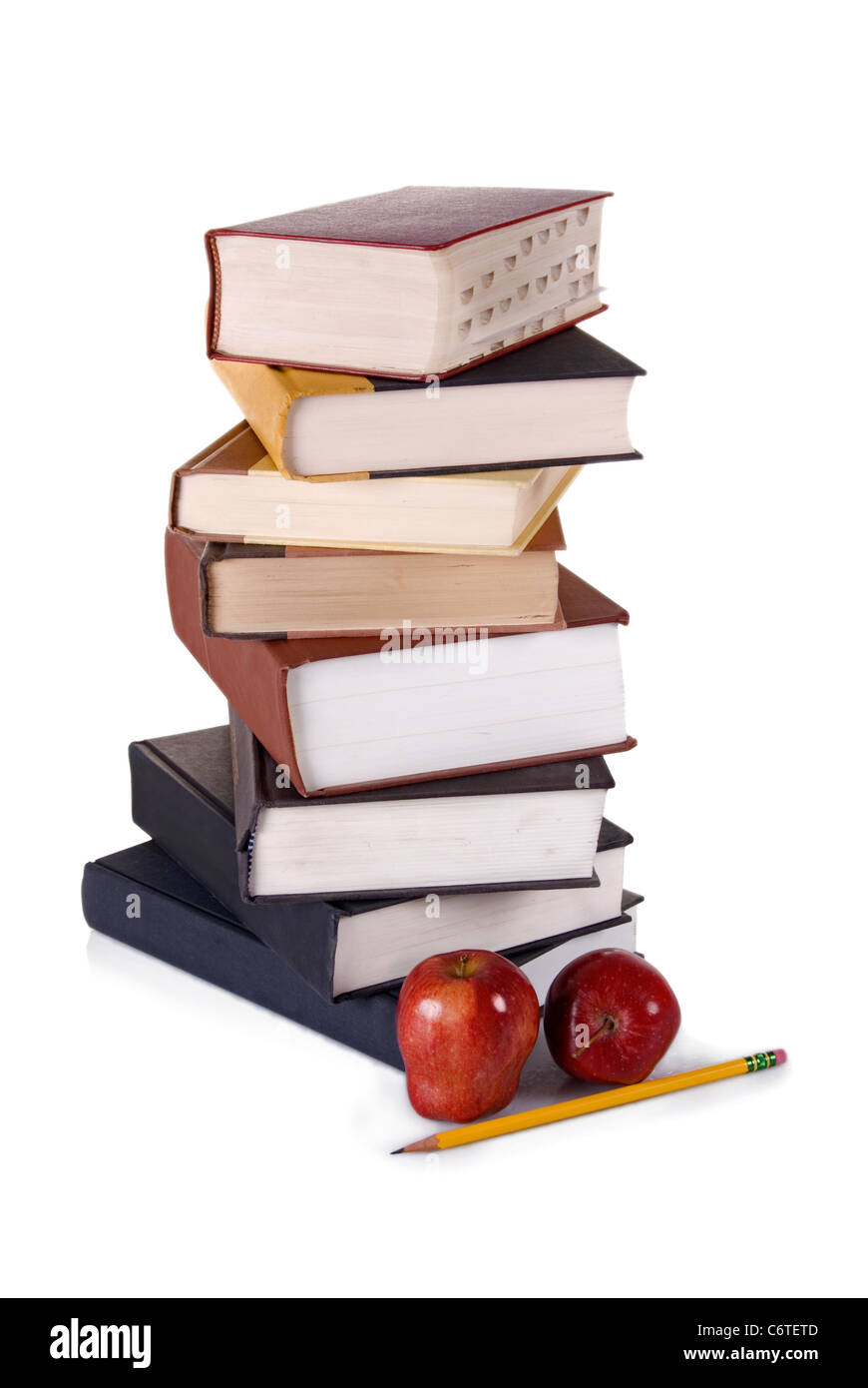 A vertical stack of hardbound books with two apples and a pencil in the ...