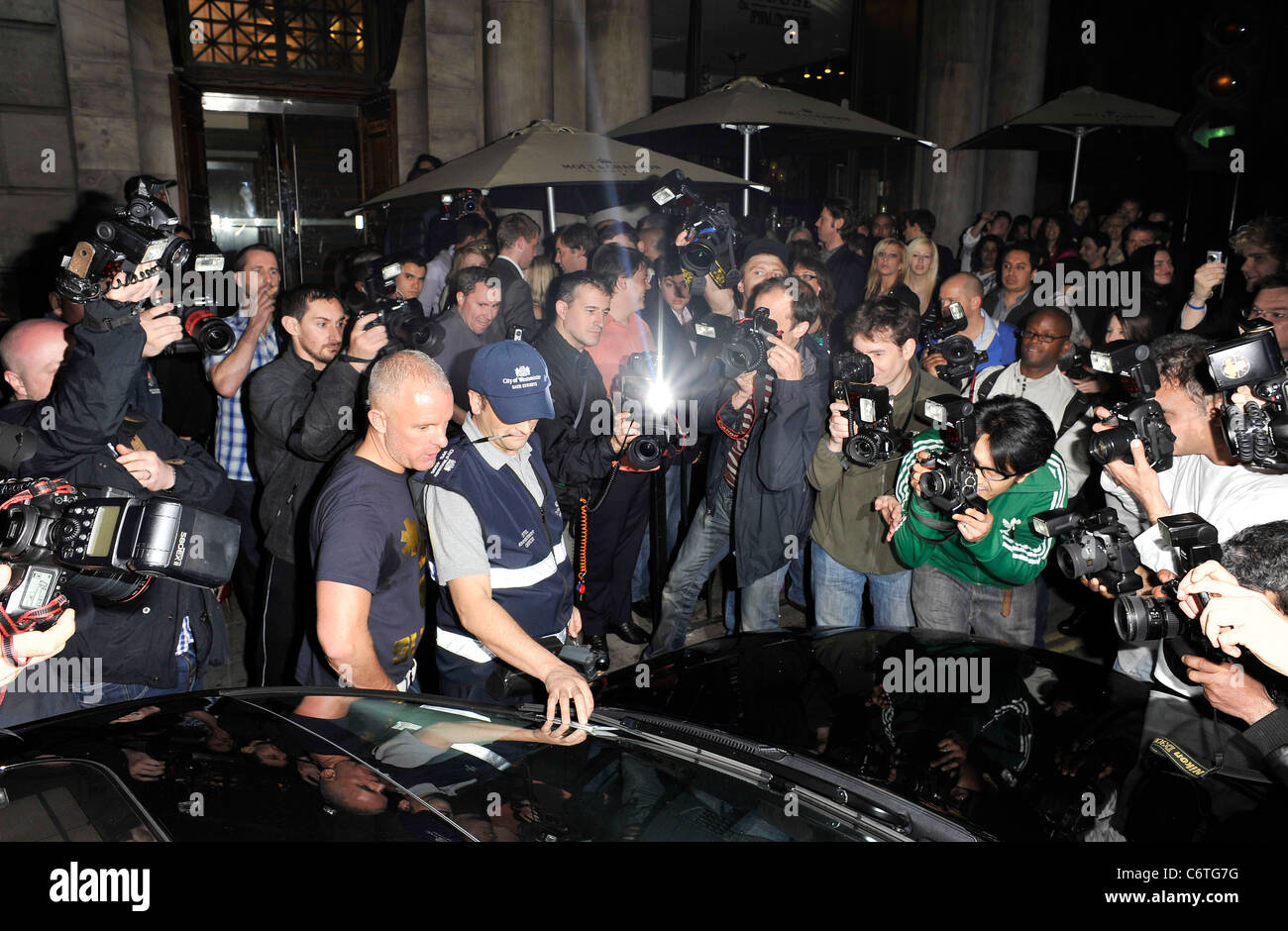 Paparazzi photographers snap away as a parking warden issues Madonna's ...