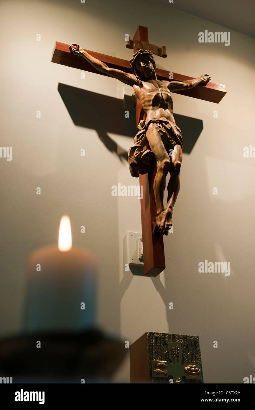 A candle burning on an alter in front of a crucifix showing Jesus on ...