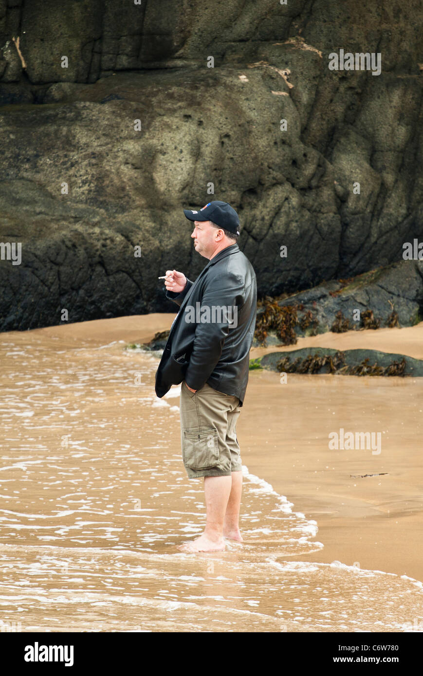 Man standing alone on beech smoking a cigarette Stock Photo - Alamy