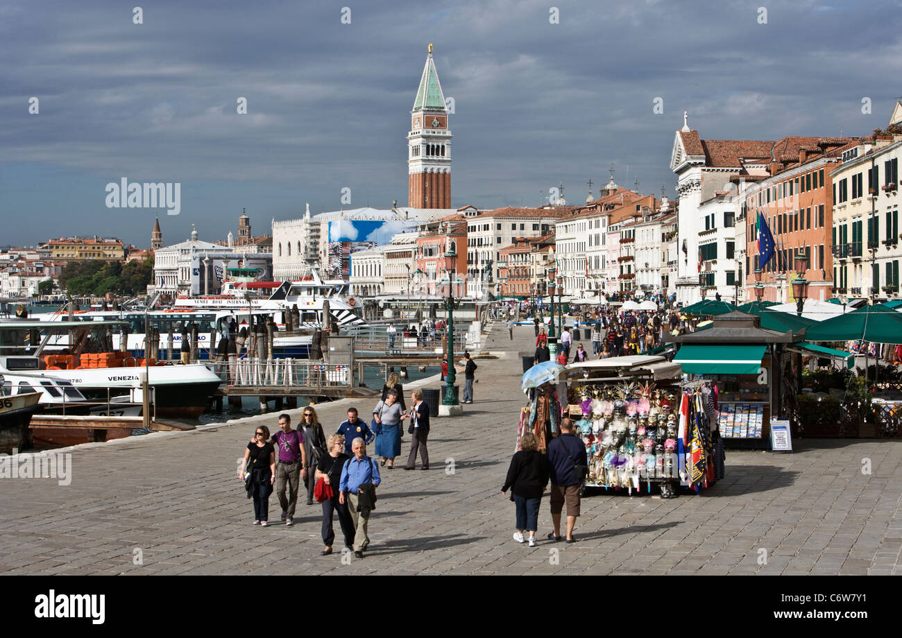 Tourists stroll past souvenir stands on the promenade alongside the ...