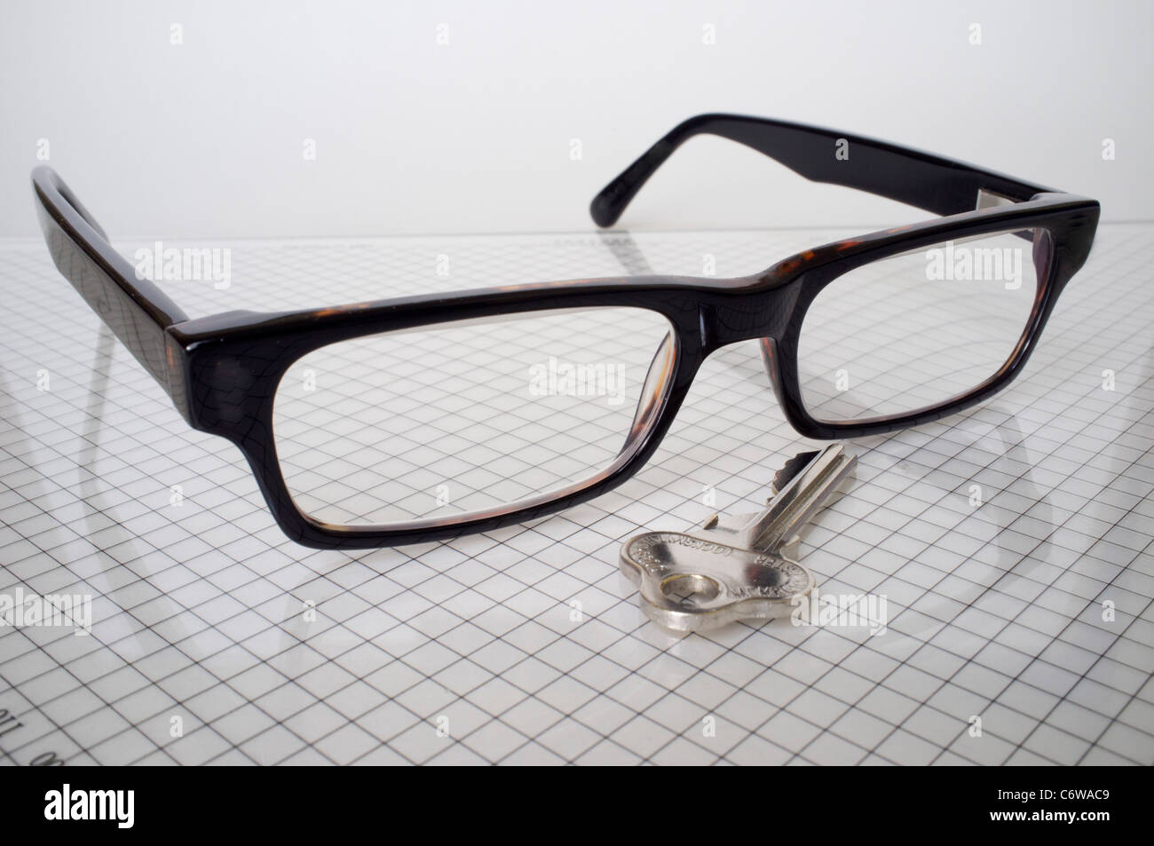 A set of reading glasses with a key on a grid Stock Photo - Alamy