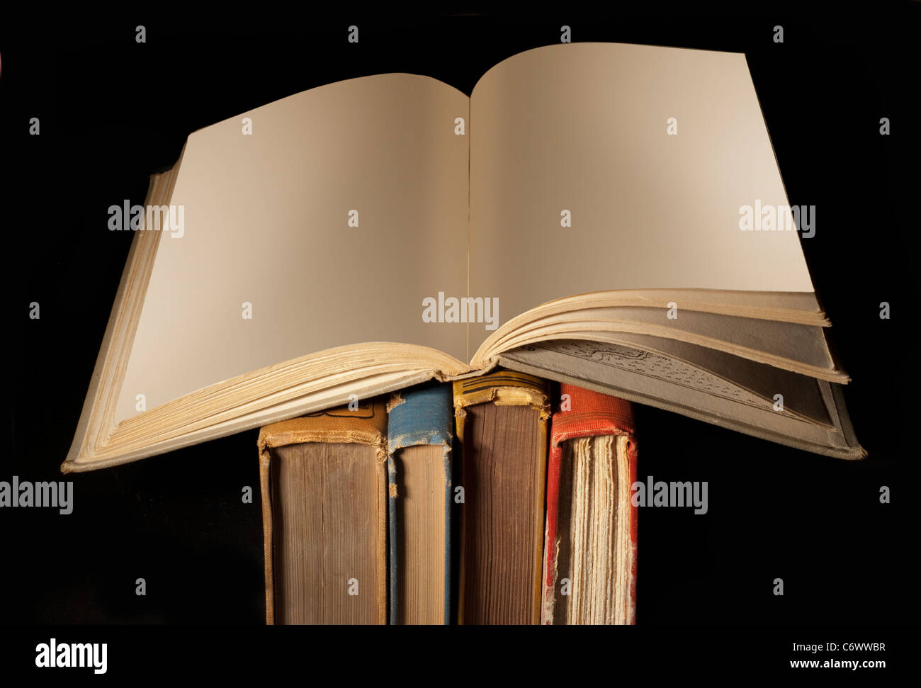 Open book on top of old textbook spines Stock Photo - Alamy