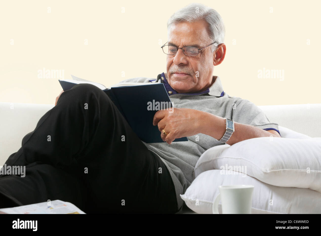 Old man reading a book on a sofa Stock Photo - Alamy